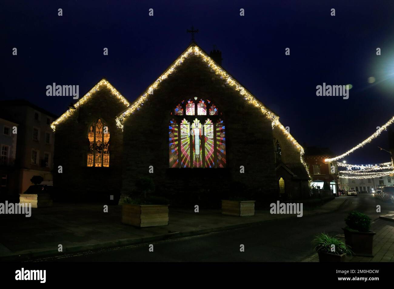 St Mary's Church, Brecon lit from within, showing stained glass windows ...