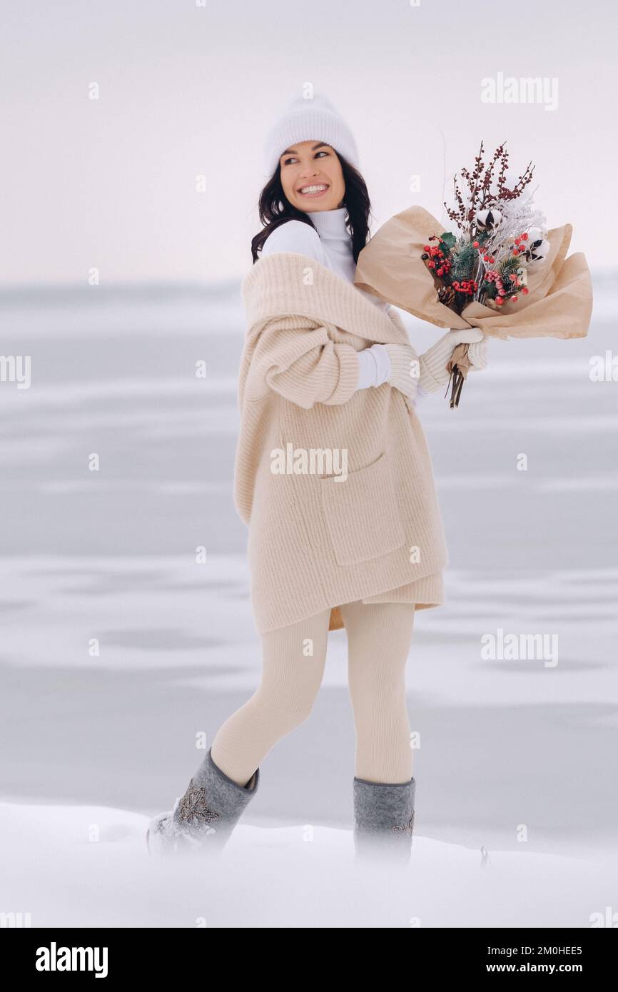 A girl in a beige cardigan and winter flowers walks in nature in the ...