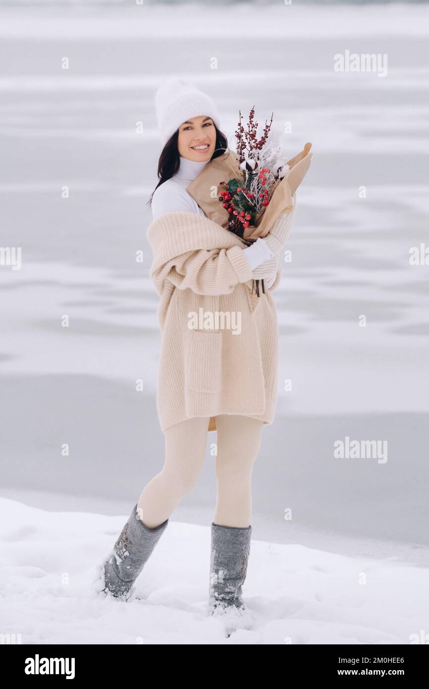 A girl in a beige cardigan and winter flowers walks in nature in the ...