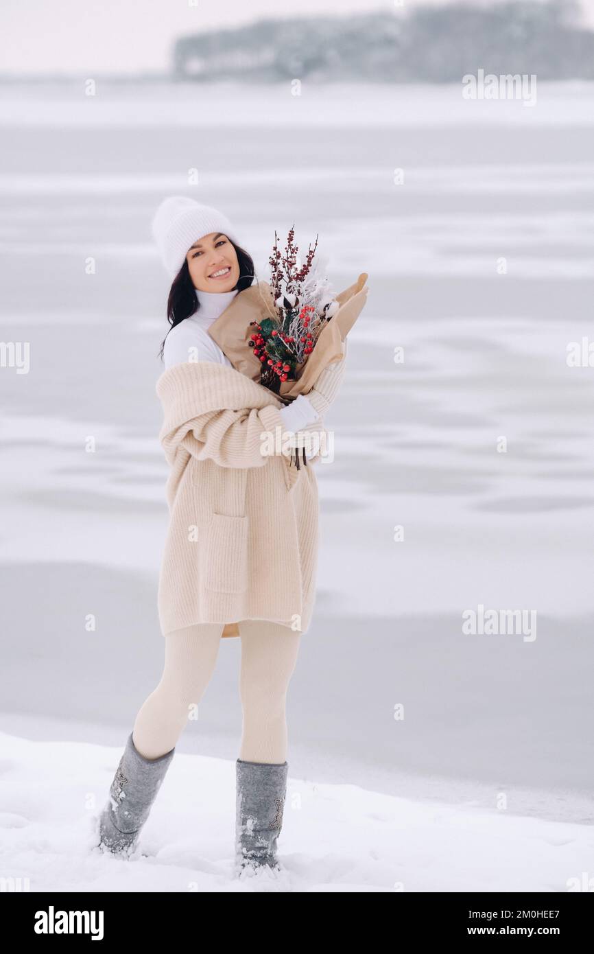 A girl in a beige cardigan and winter flowers walks in nature in the ...