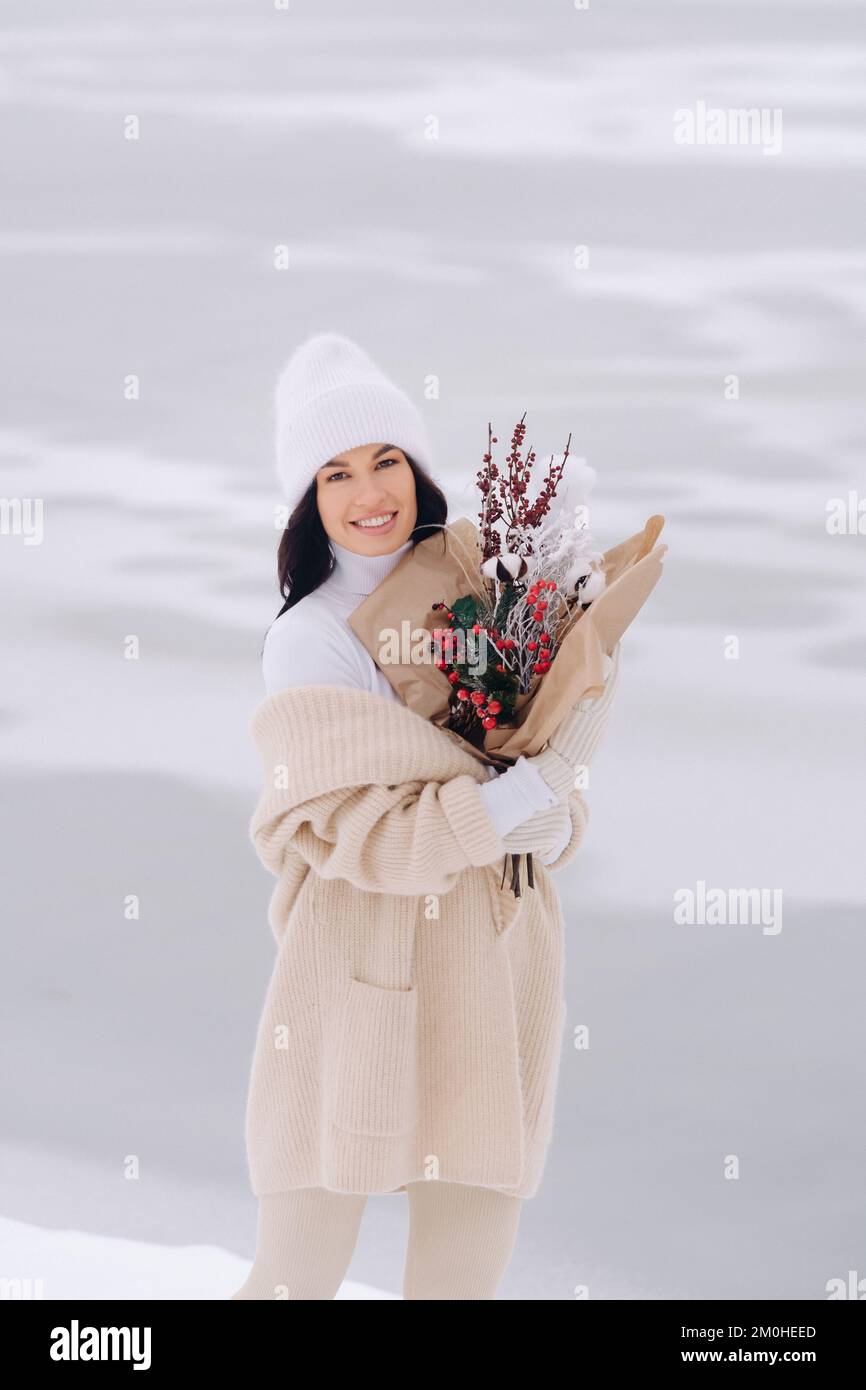 A girl in a beige cardigan and winter flowers walks in nature in the ...