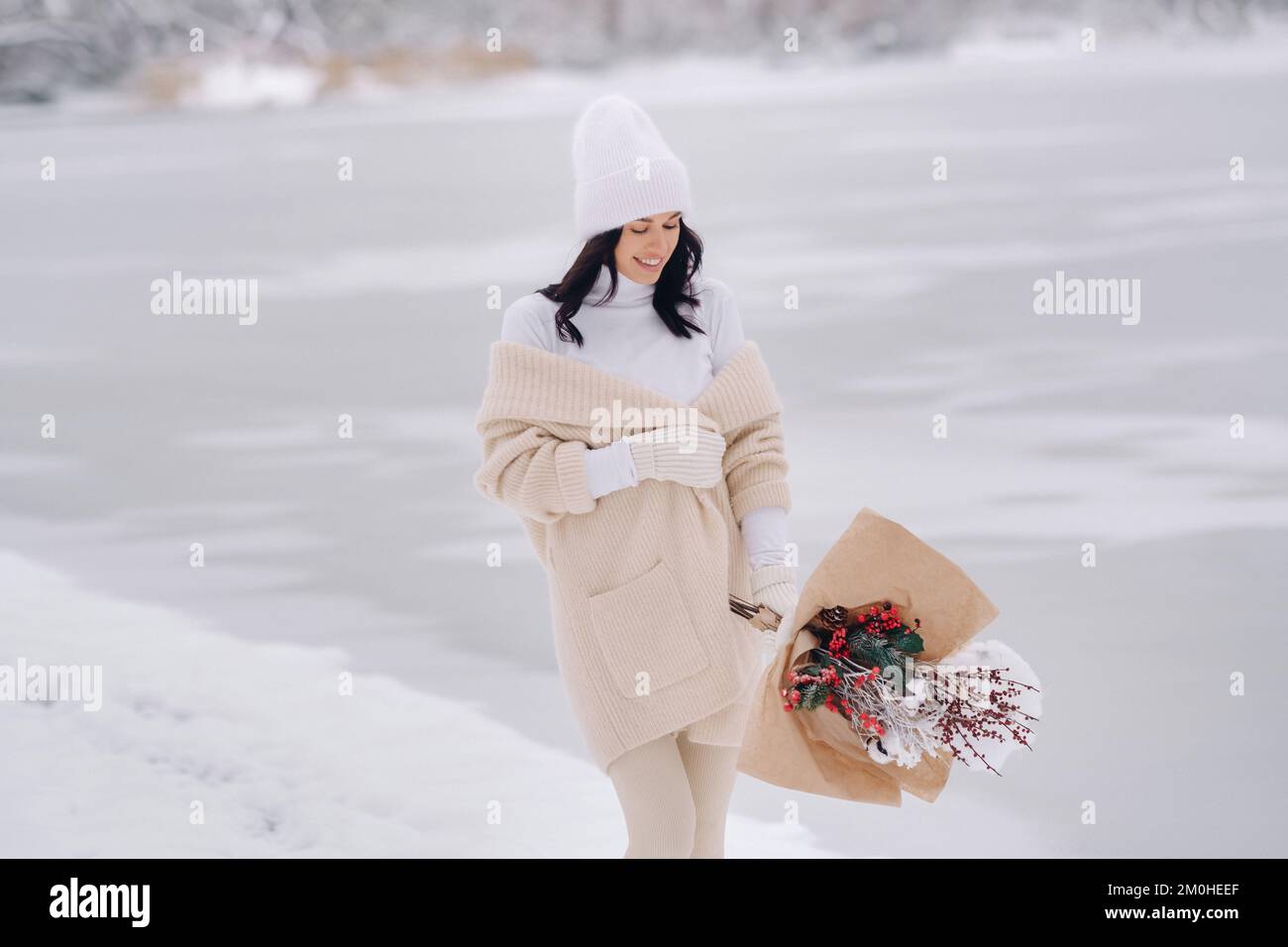 A girl in a beige cardigan and winter flowers walks in nature in the ...
