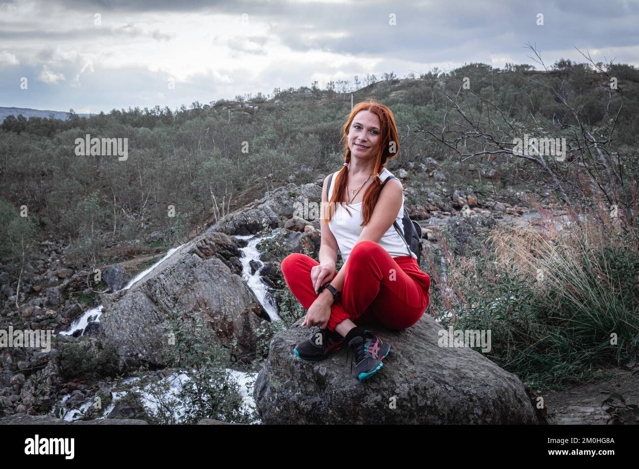 Pretty woman sitting on a stone in yoga pose against the vast forest ...