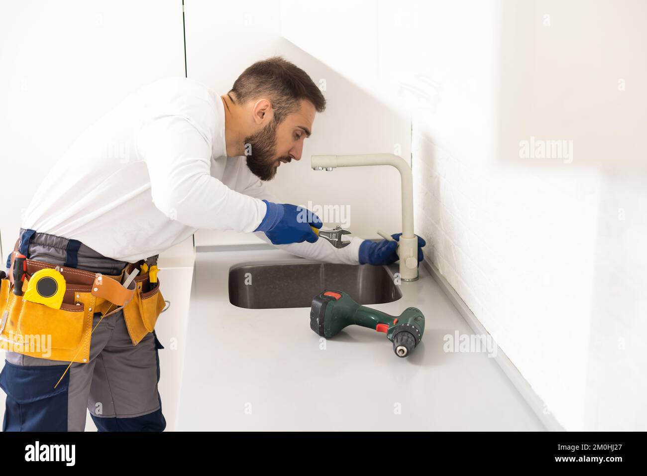 Side View Of A Plumber Fixing Water Tap In Kitchen Stock Photo - Alamy