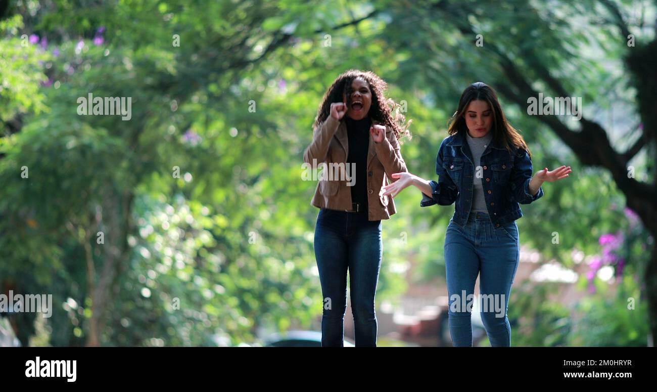 Excited two young women celebrating good news. Diverse girls dancing ...