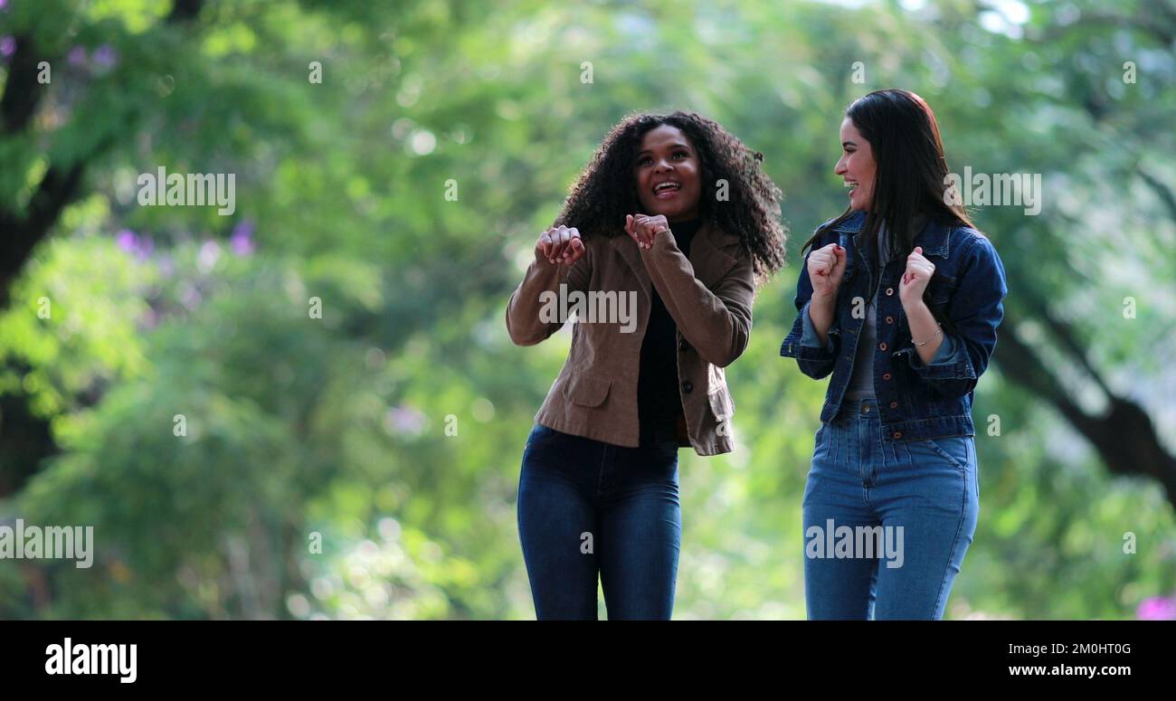 Excited two young women celebrating good news. Diverse girls dancing ...