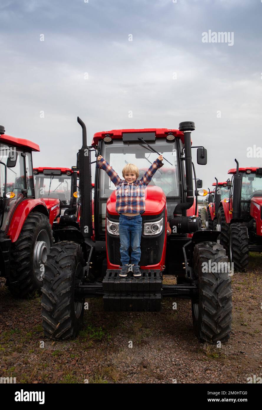 Presentation and sale of new red tractors standing in a row. The child ...