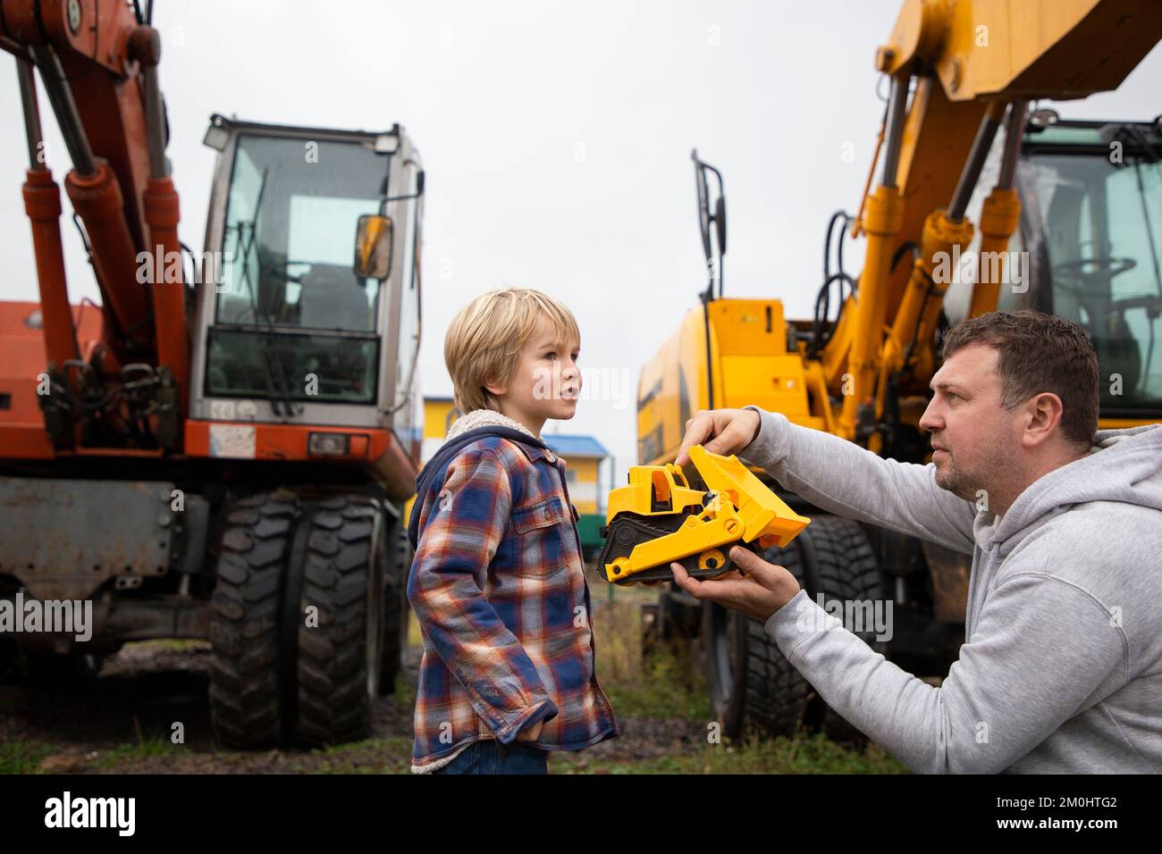 Dad and son, against background of construction equipment - excavators ...