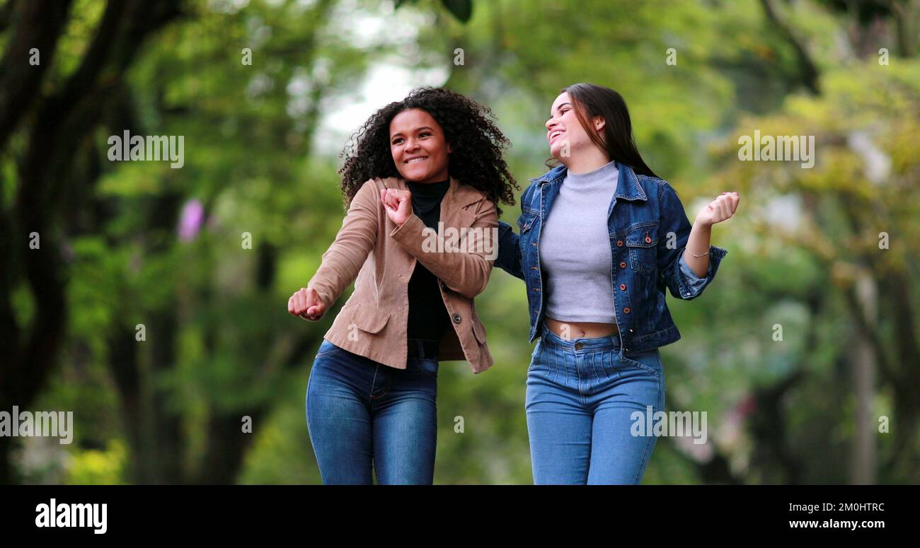 Fun happy two diverse girlfriends jumping and dancing in joy. People ...