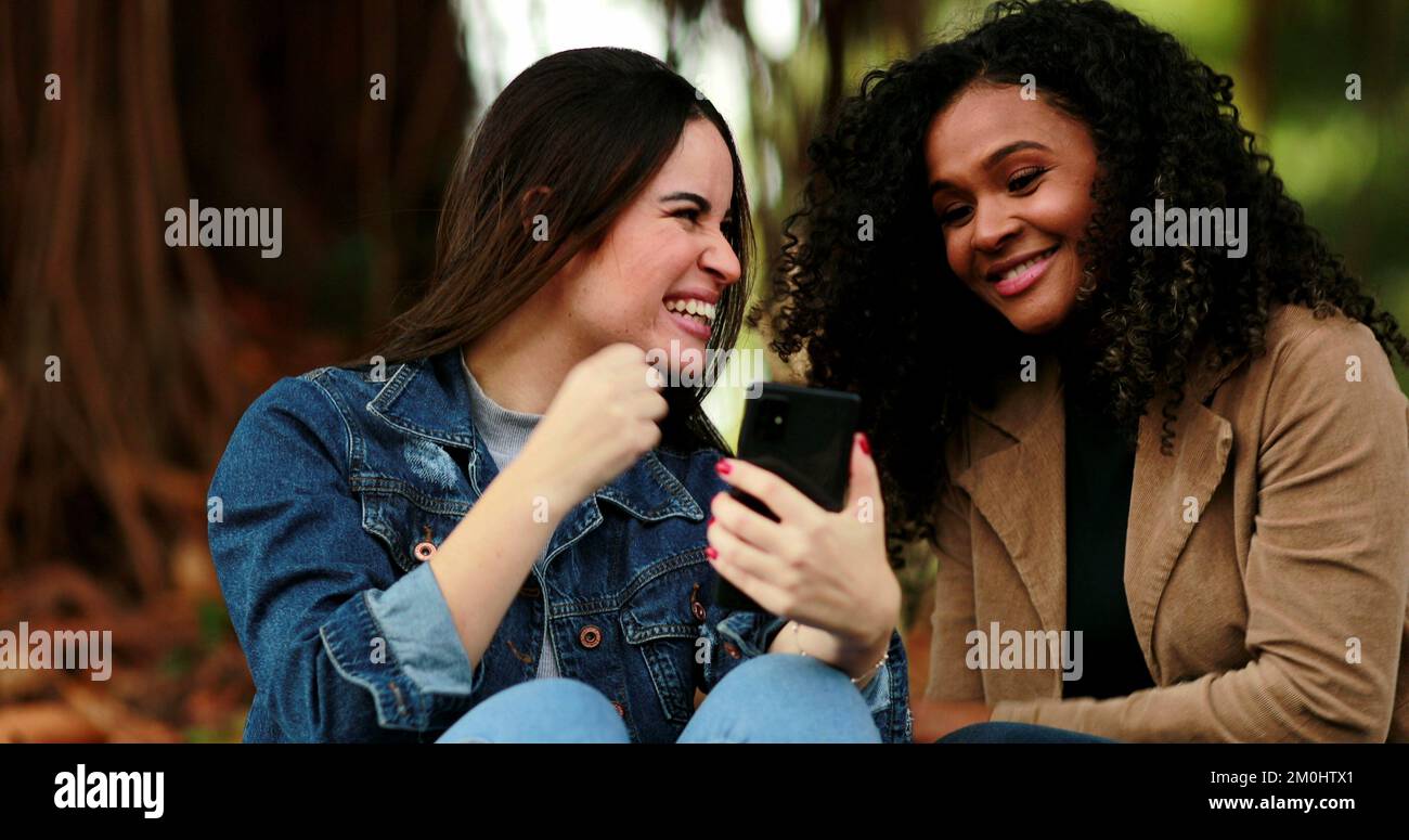 Diverse girls looking at cellphone screen. Woman calling friend to ...