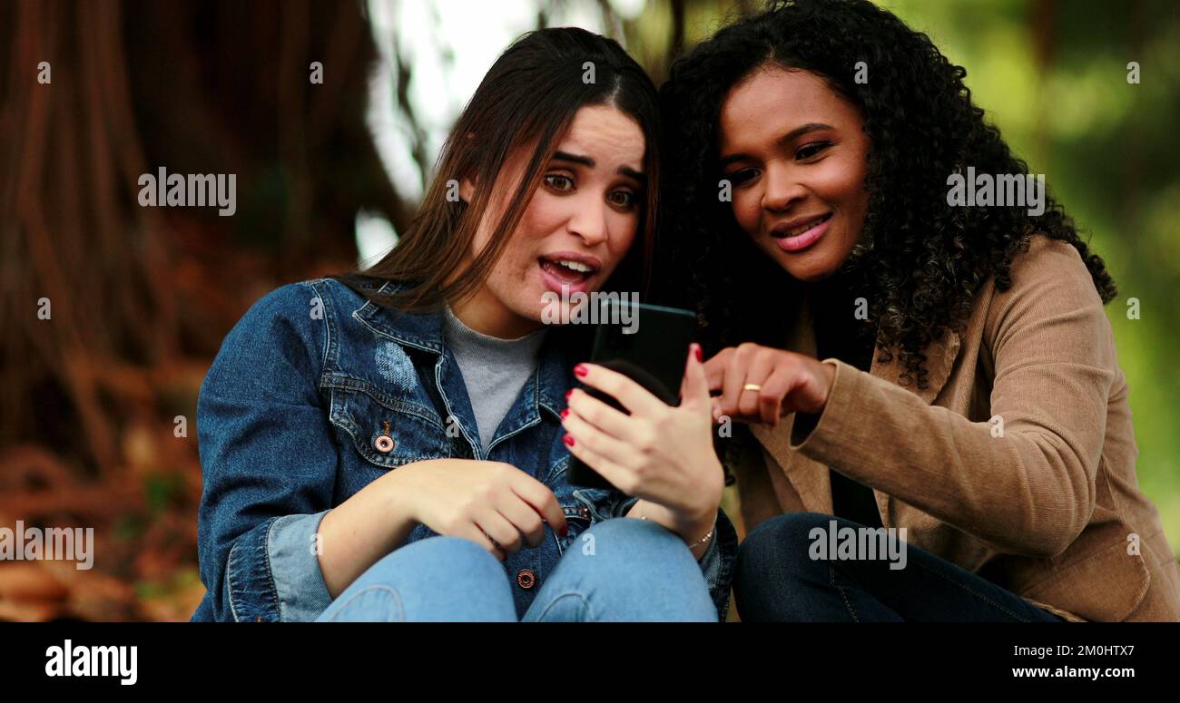 Diverse girls looking at cellphone screen. Woman calling friend to ...