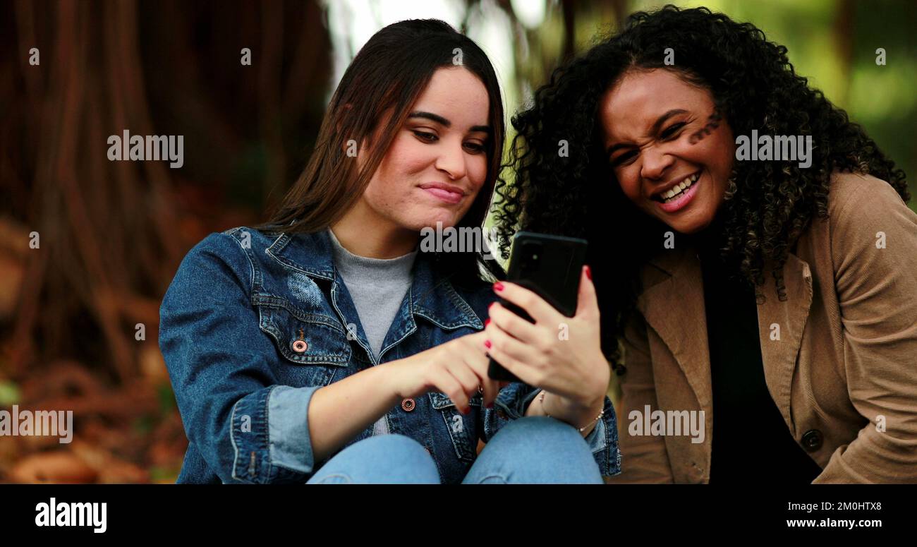 Diverse girls looking at cellphone screen. Woman calling friend to ...
