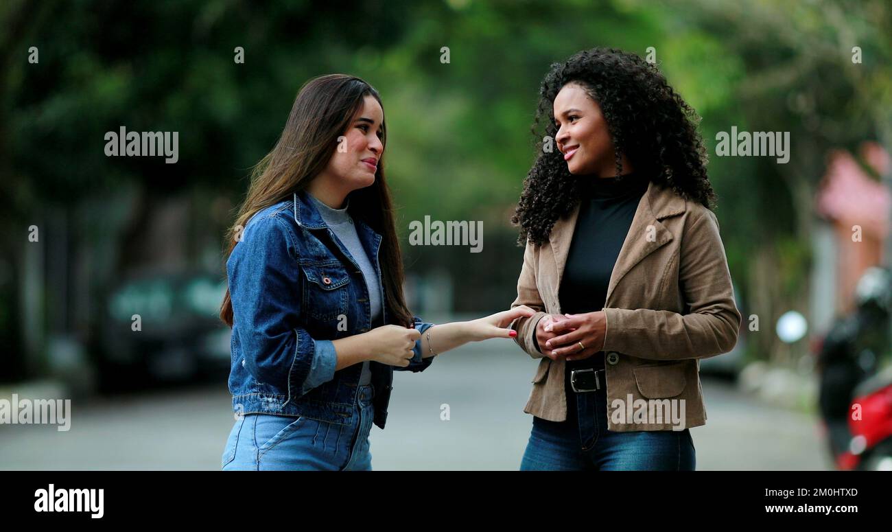 Diverse friendship, two women talking outside at park Stock Photo - Alamy