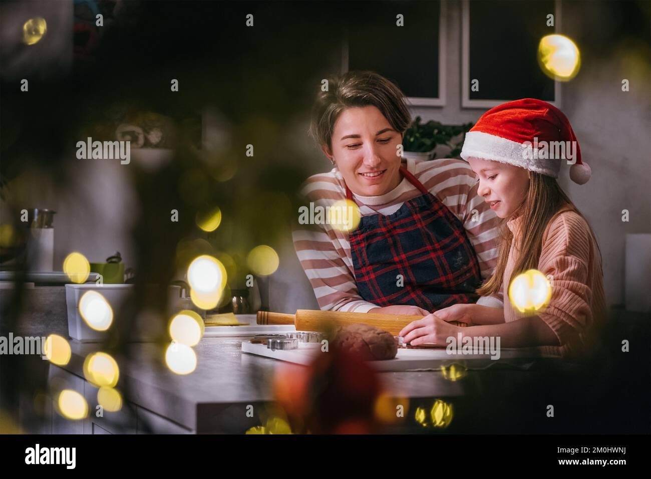 Cute little girl in red Santa hat with mother making homemade Christmas ...