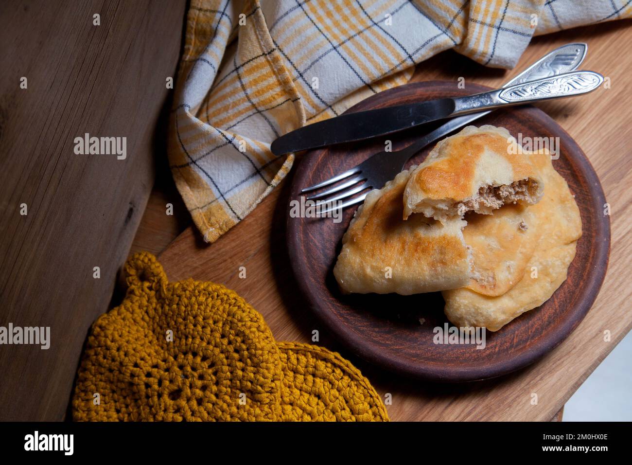 Clay plate with two of individual fried pies with meat on wooden table ...