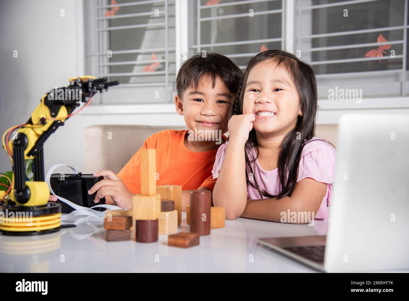 Kid little girl program code to robot with laptop computer and the boy ...