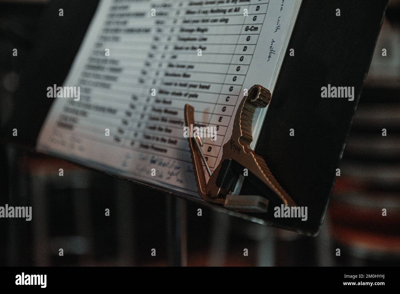 A closeup of a golden guitar capo on a musical note stand Stock Photo ...