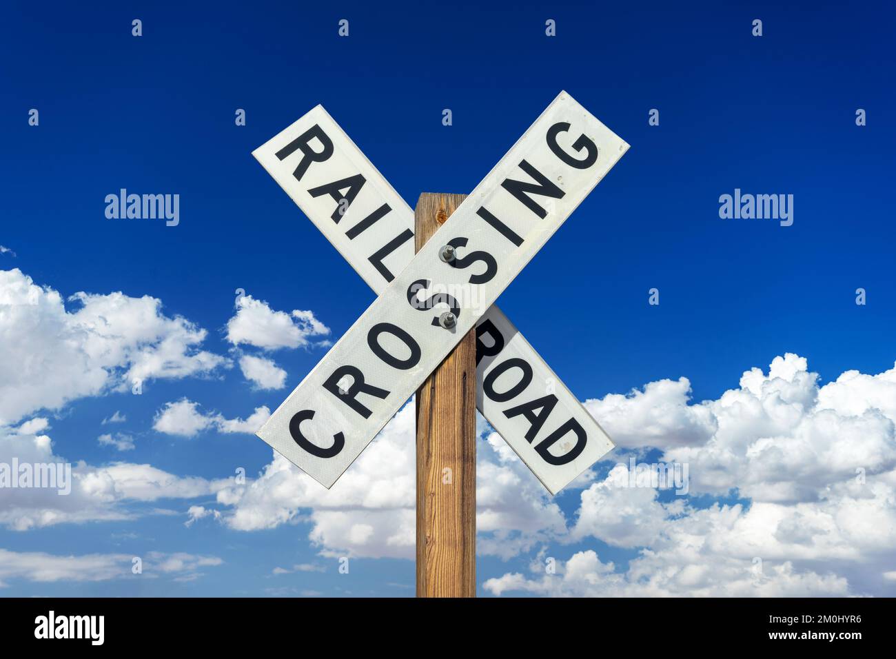 Railroad Crossing road sign on a wooden post with blue sky and clouds ...