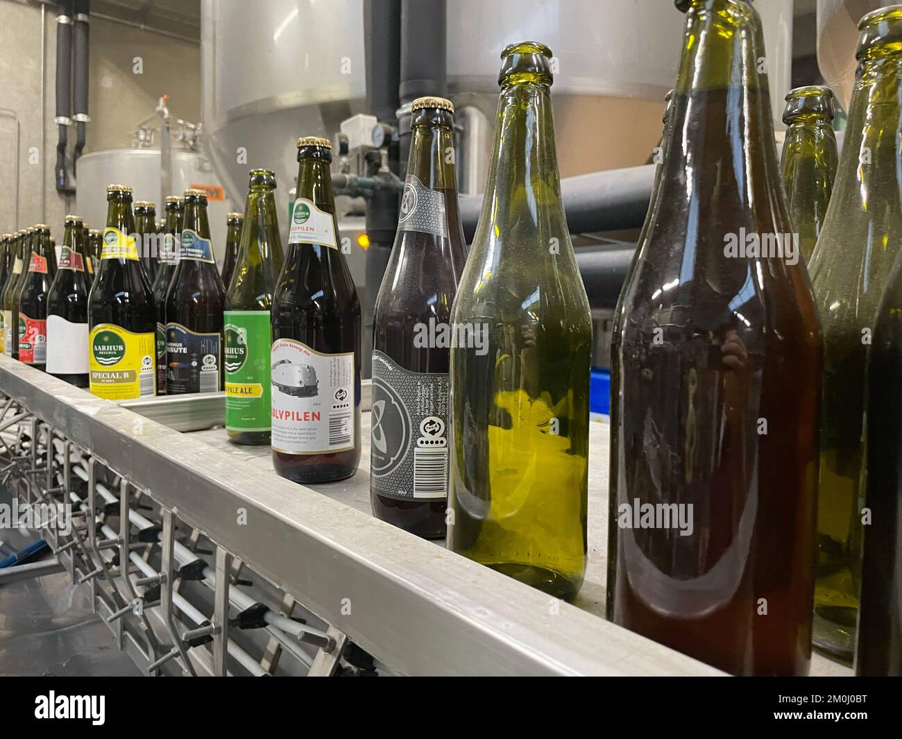 A beer glass bottle filler machine and lots of bottles in a line Stock ...