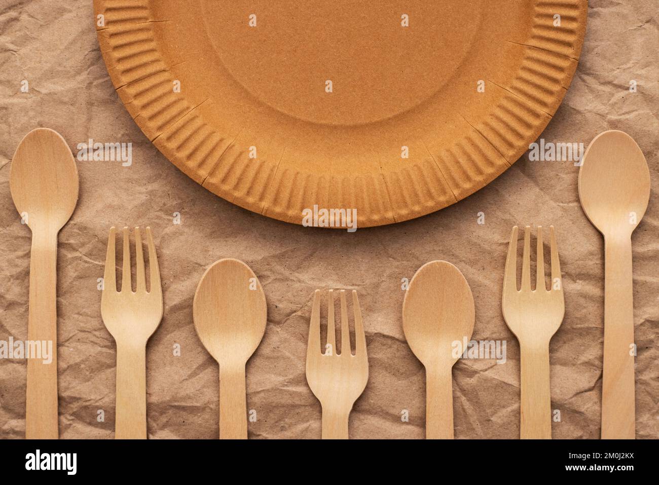 Wooden forks and spoons and paper plate on crumpled paper Stock Photo ...