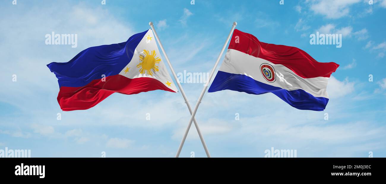 two crossed flags Paraguay and Philippines waving in wind at cloudy sky ...