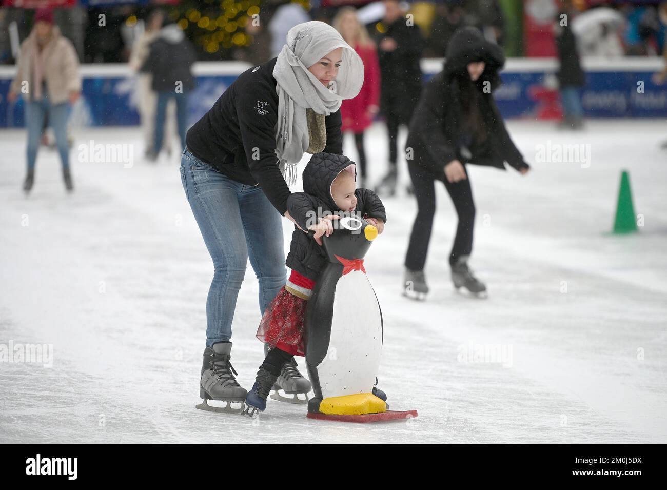 A young girl holds on to a penguin skating aid as takes to the ice at ...