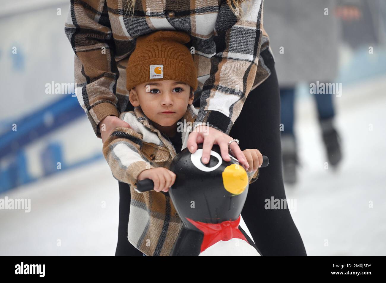 A young boy holds on to a penguin skating aid as takes to the ice at ...