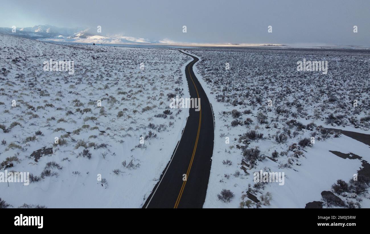 An aerial view of a long asphalt road through a snowy field Stock Photo ...