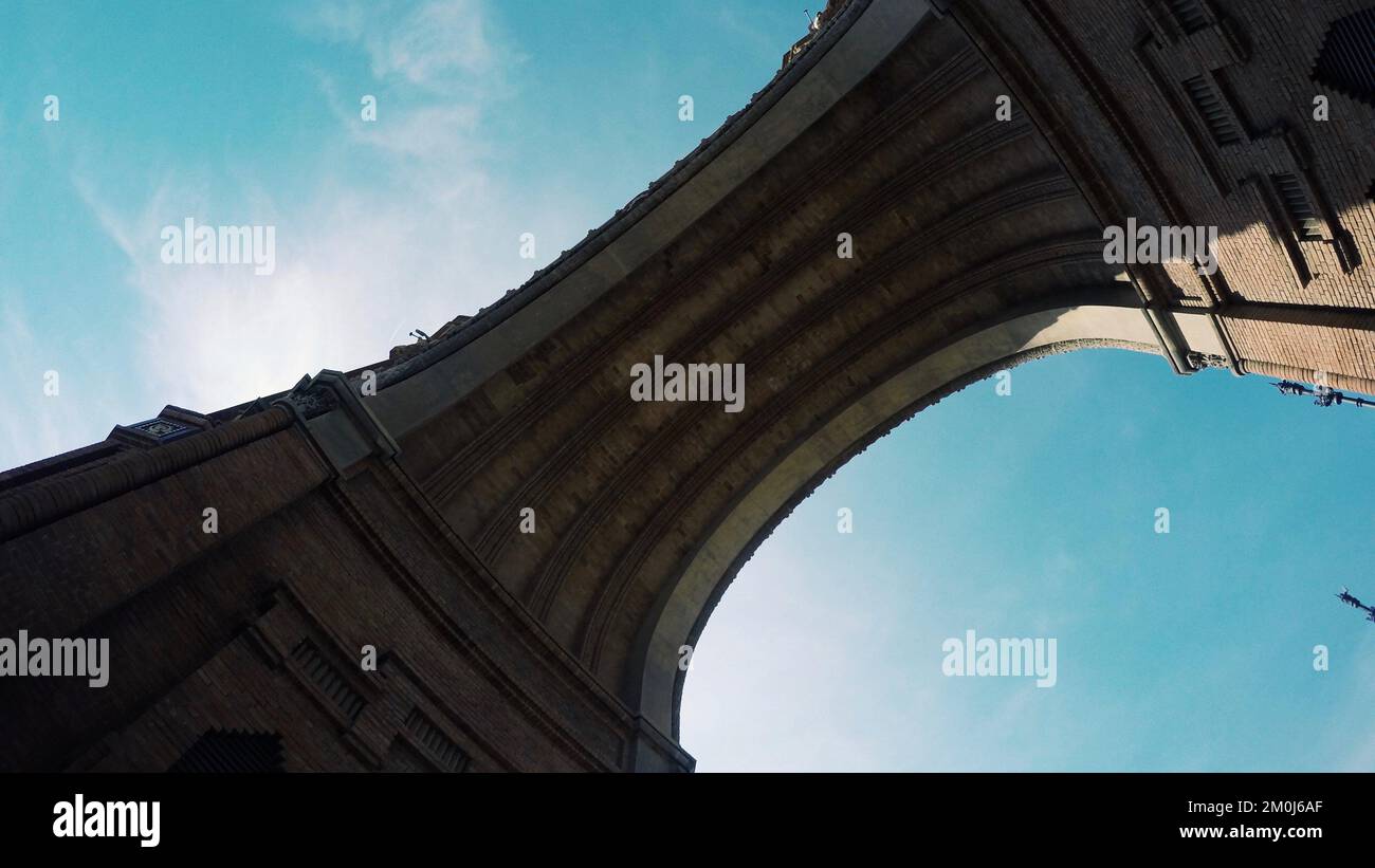 A low-angle shot of an arch-building structure against a cloudy blue ...