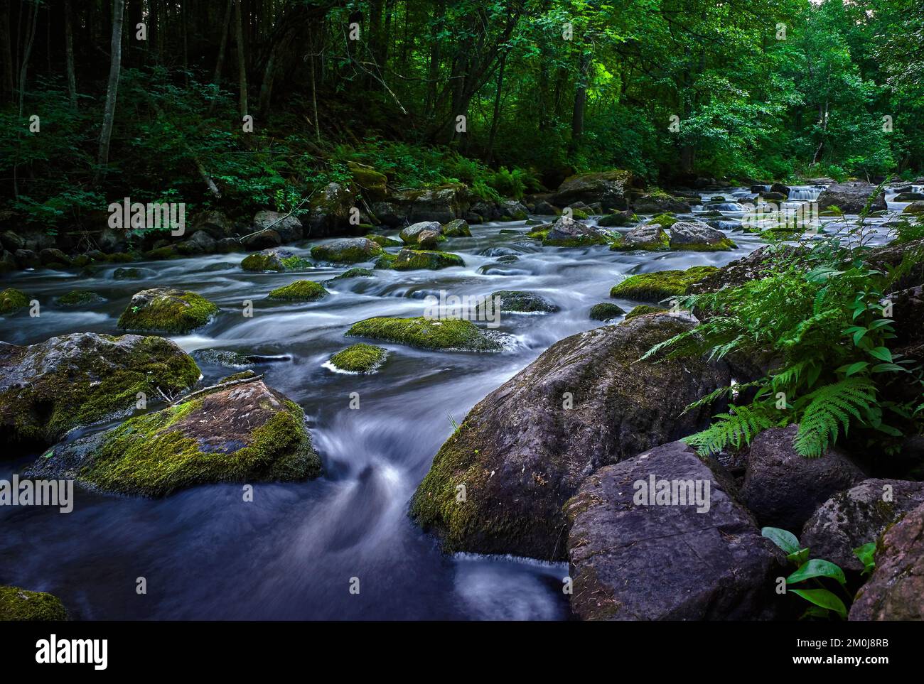 a light exposure stream of water over rocks Stock Photo - Alamy