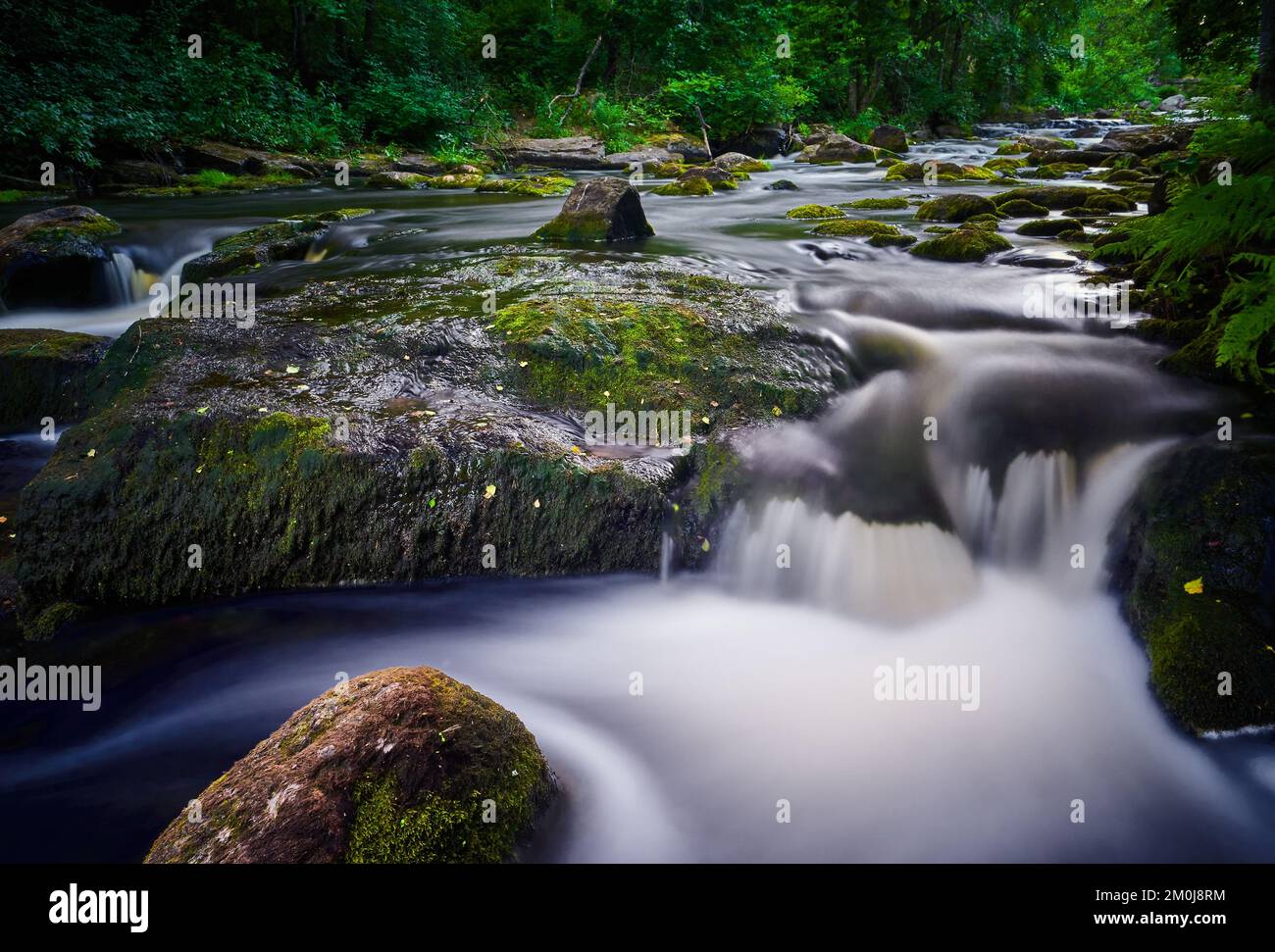 A light exposure stream of water over rocks Stock Photo - Alamy