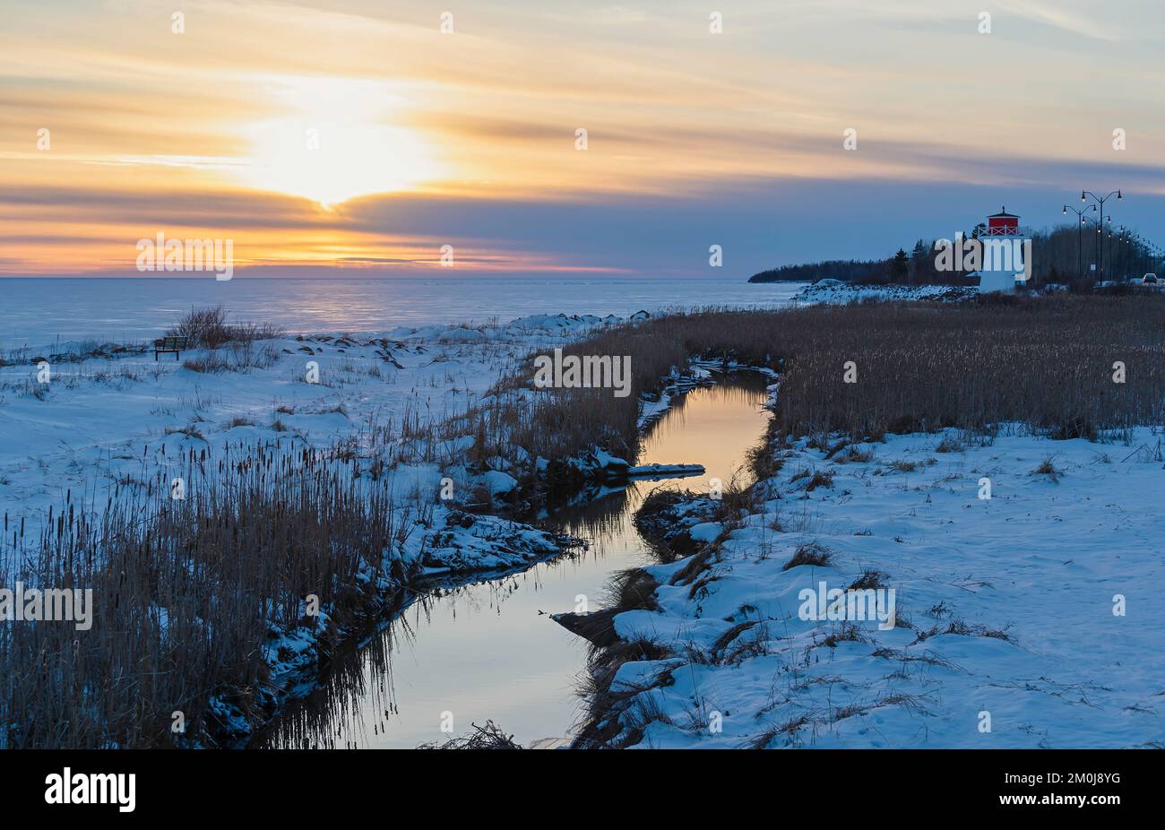 Stream running through a salt marsh into the ocean with a lighthouse in ...