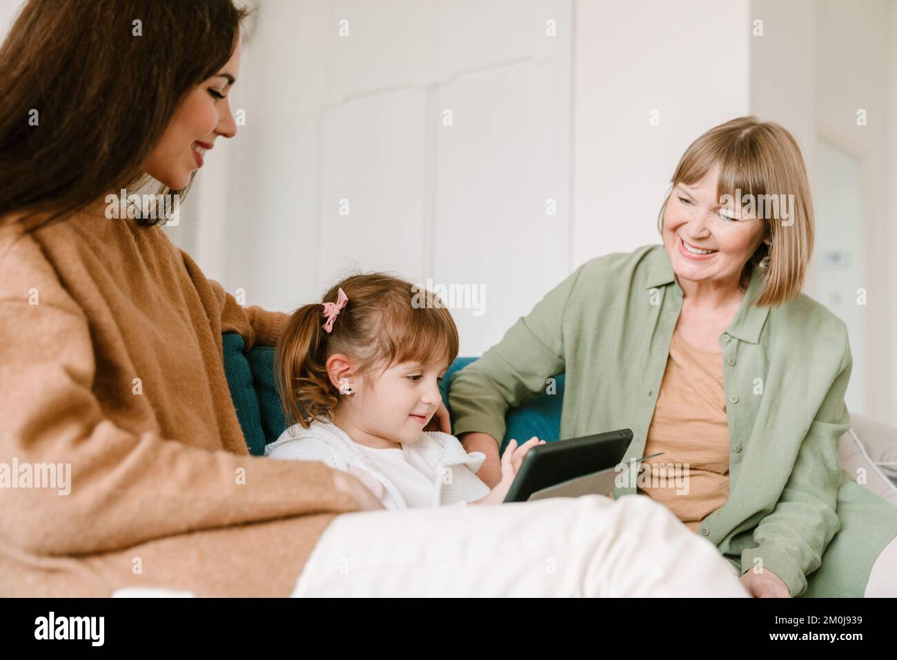 White girl using tablet computer while spending time with her family at ...