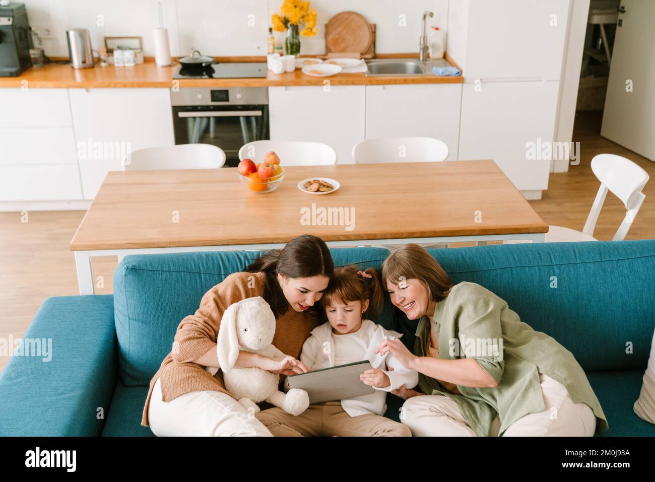 White girl using tablet computer while spending time with her family at ...