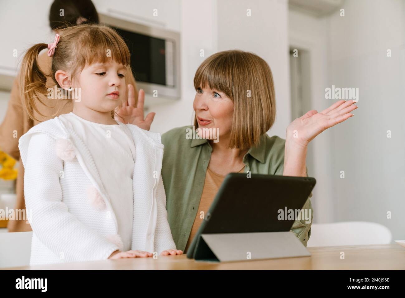White girl using tablet computer while spending time with her family at ...