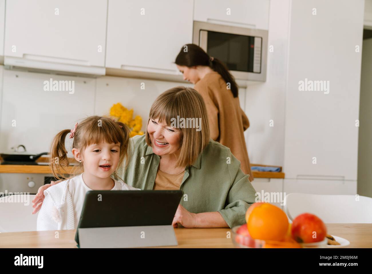 White girl using tablet computer while spending time with her family at ...