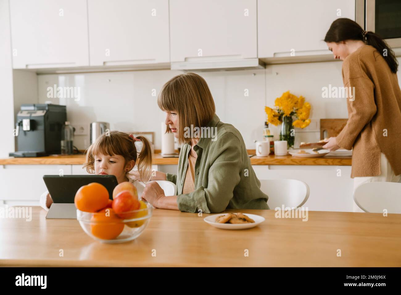 White girl using tablet computer while spending time with her family at ...