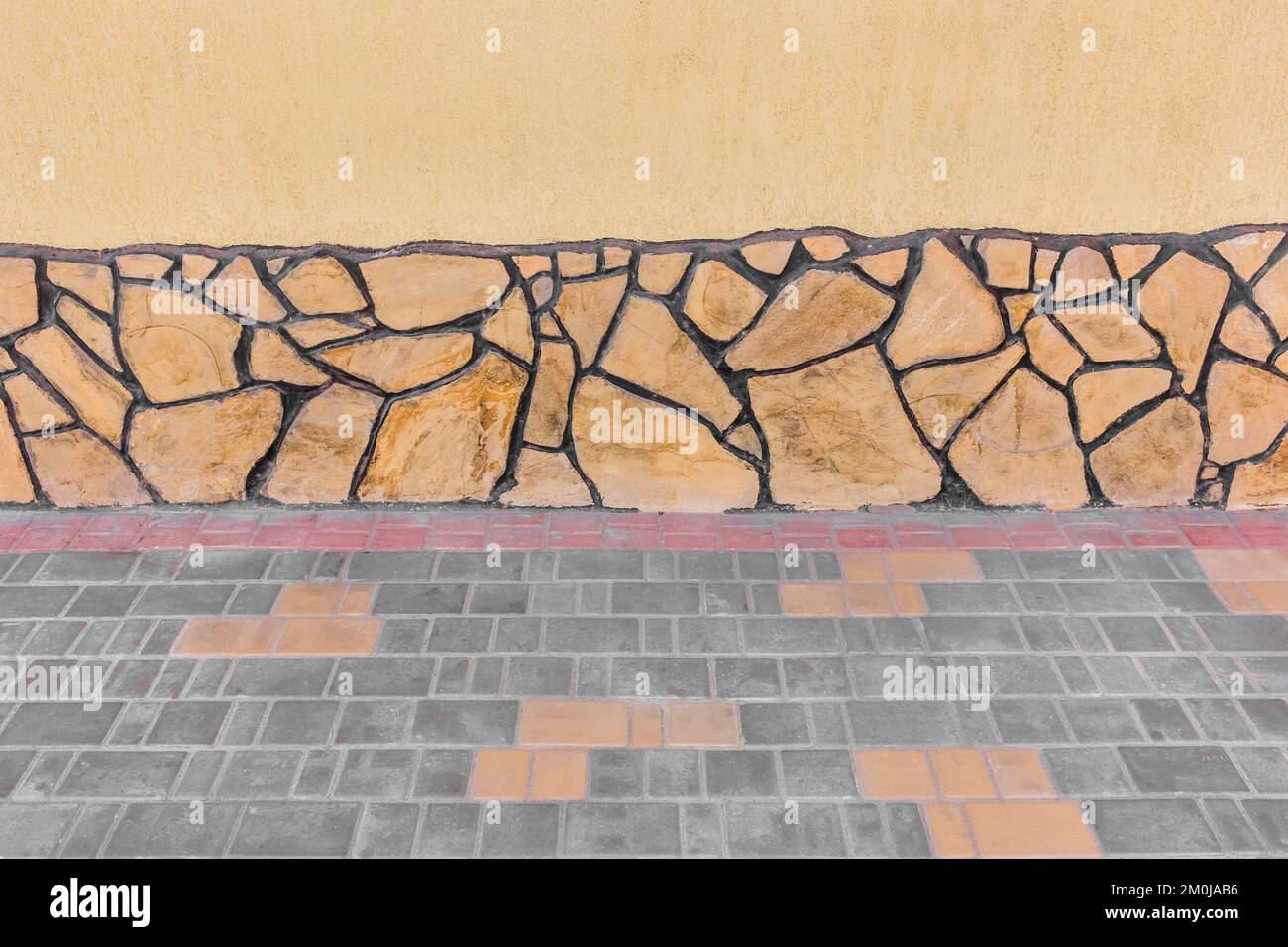 Facade of modern building with beige plaster wall, stone abstract pattern and paving slabs floor ...