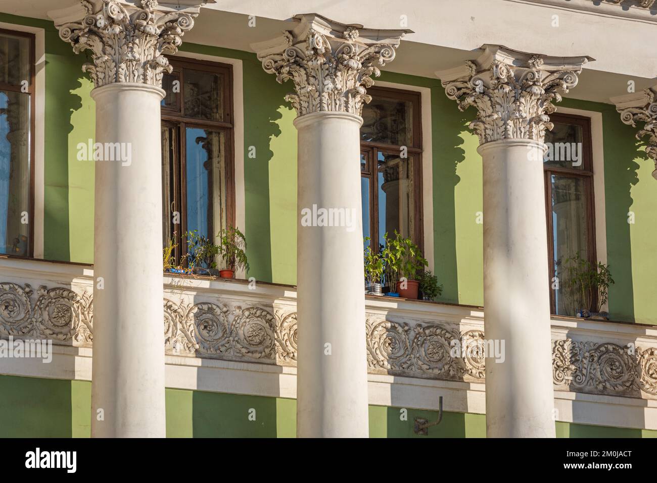 Tomatoes grow in plastic containers in windows between massive columns ...