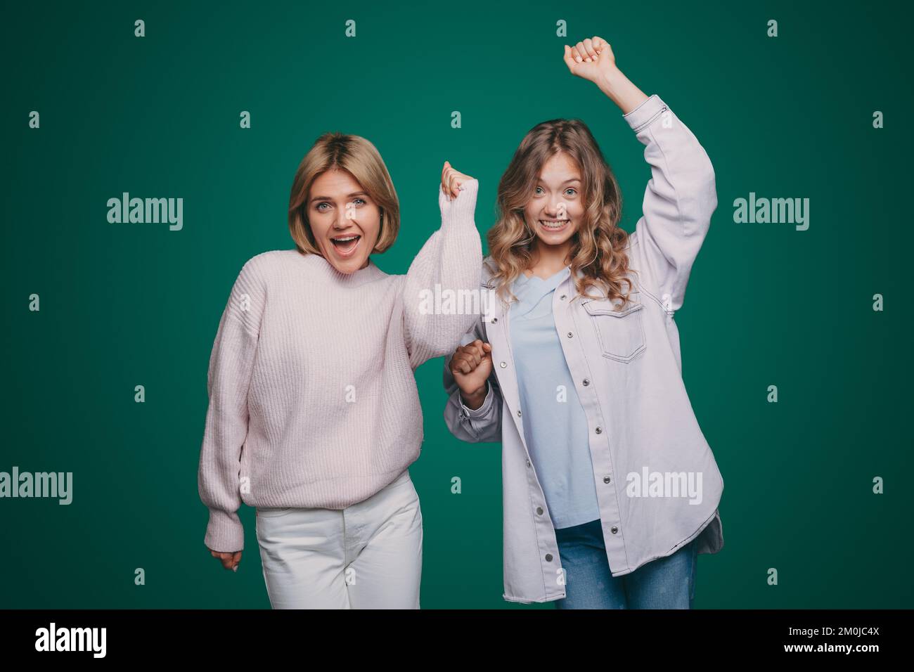 Portrait of two happy smiling laughing women celebrating over green ...