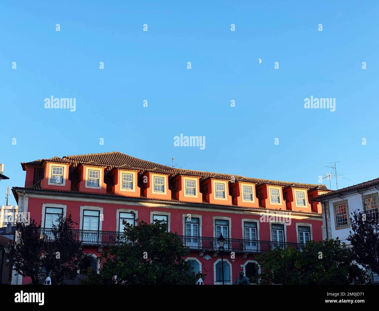 A scene of the red building with many windows illuminated by sun rays ...