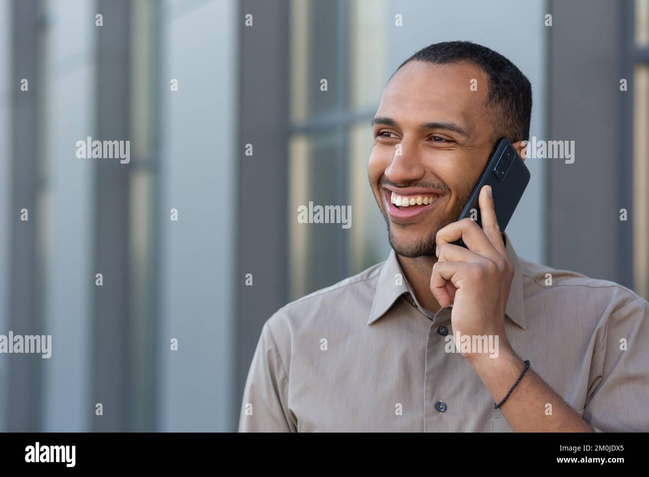 Cheerful and smiling African American office worker talking on the ...