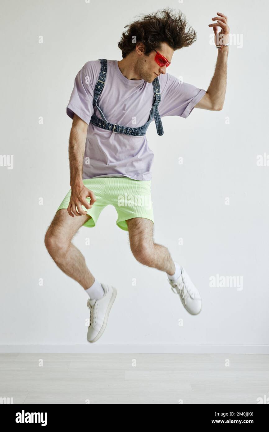 Vertical action shot of young man jumping in air wearing colorful ...