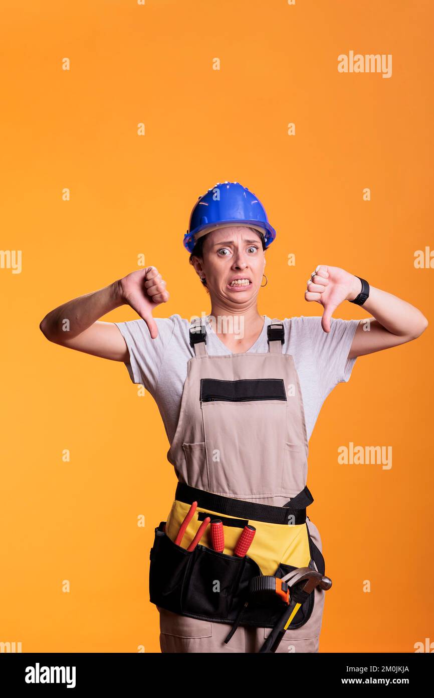 Discontent construction worker showing thumbs down sign, standing over ...