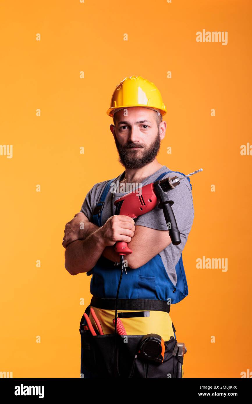 Professional builder posing on camera with power drill, acting ...