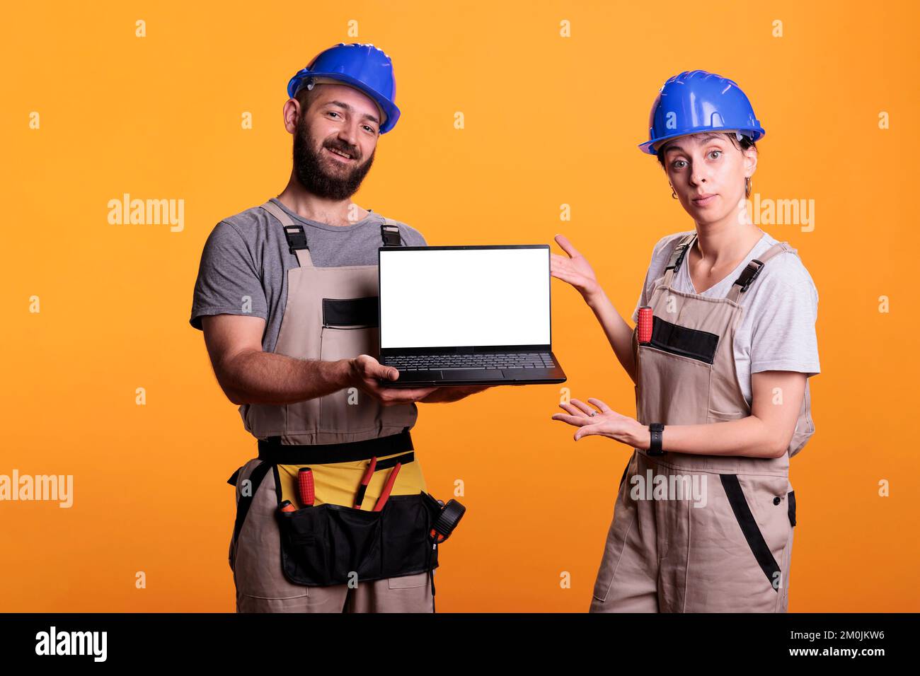 Construction workers holding laptop with white display, wearing ...
