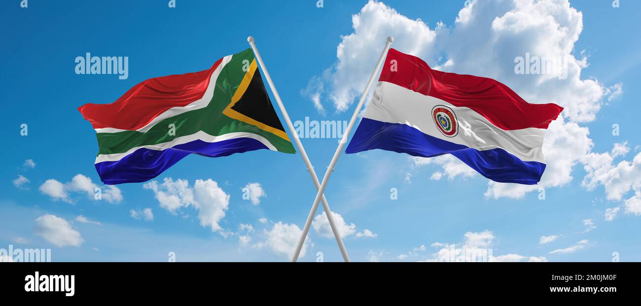 two crossed flags Paraguay and South Africa waving in wind at cloudy ...