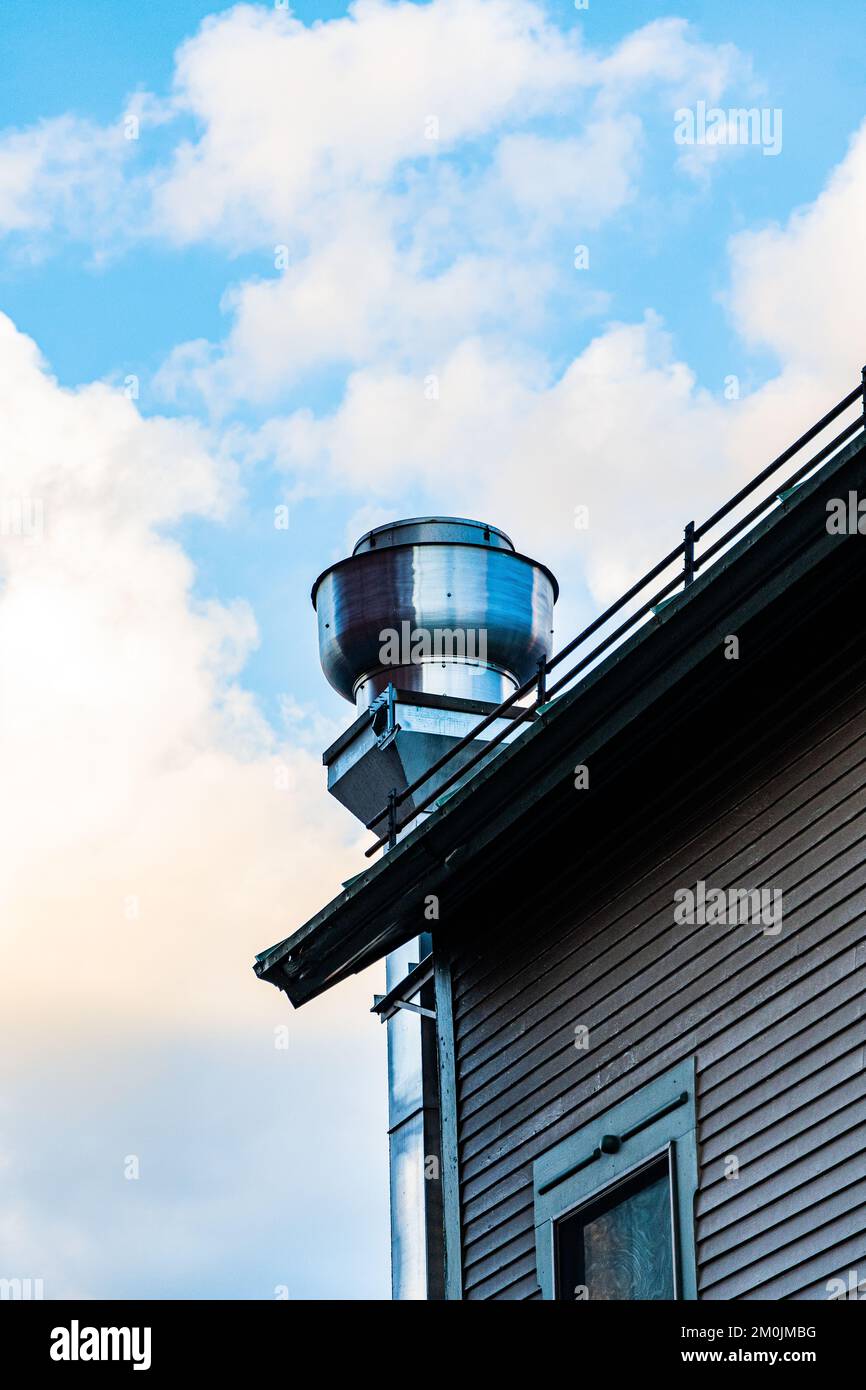 metal chimney behind house roof under cloudy blue sky Stock Photo - Alamy