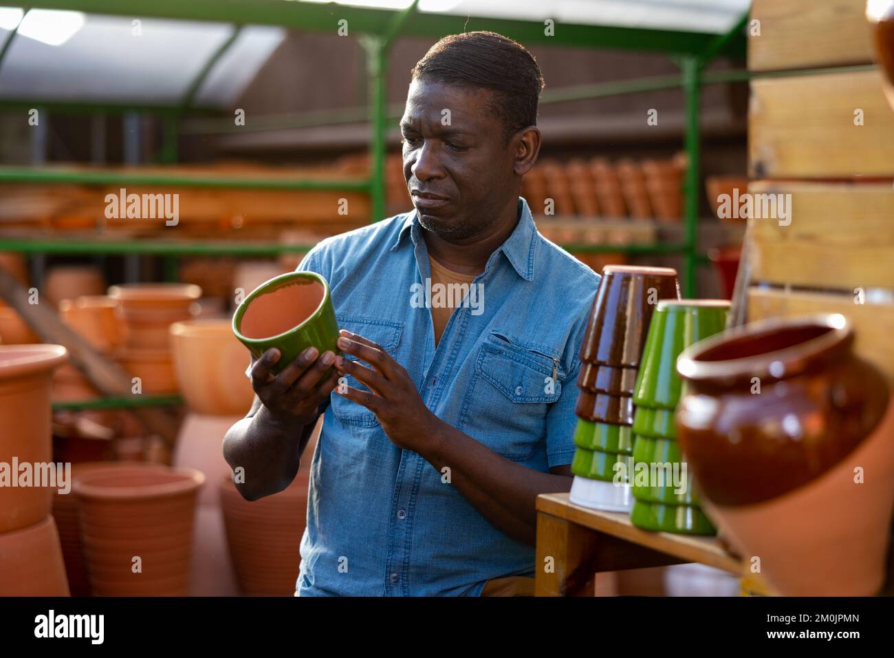 African american man chooses flower pots for indoor plants Stock Photo ...