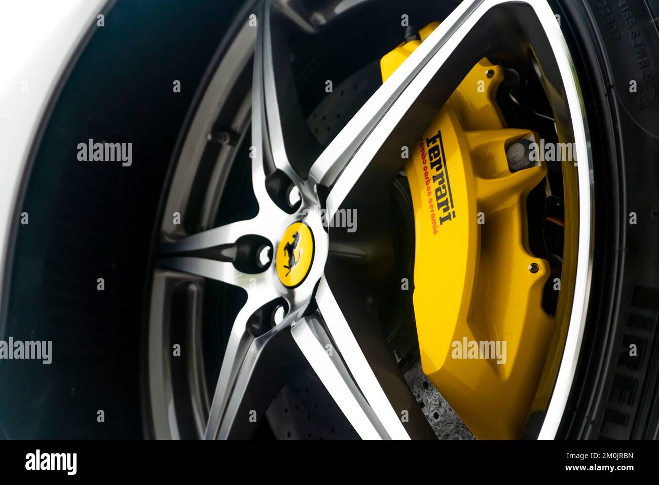 A closeup of the aluminum wheel with yellow brake caliper of a Ferrari ...